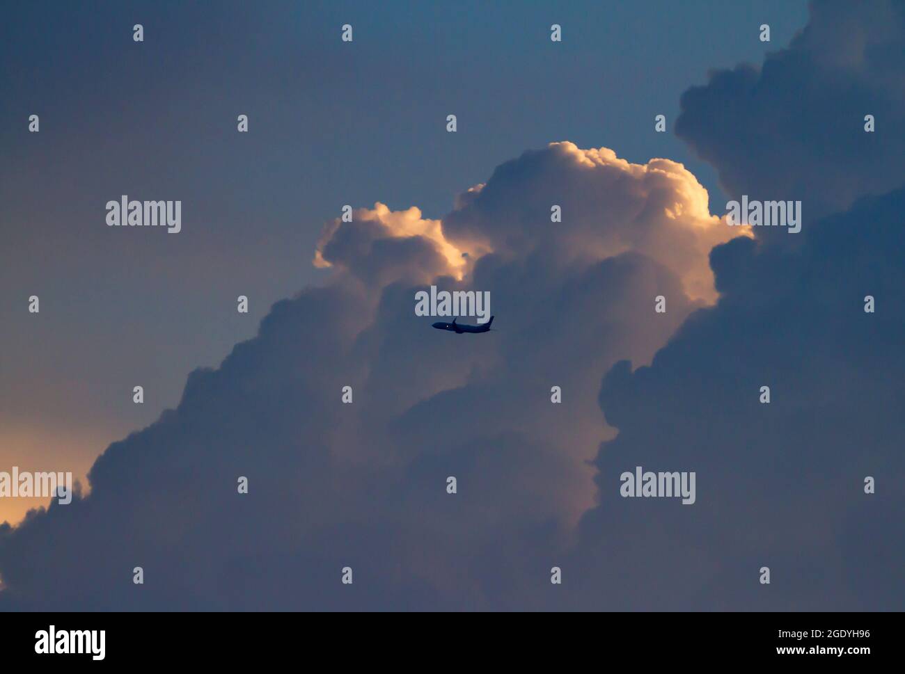A commercial airliner passes by a large thunderhead cloud shortly after ...