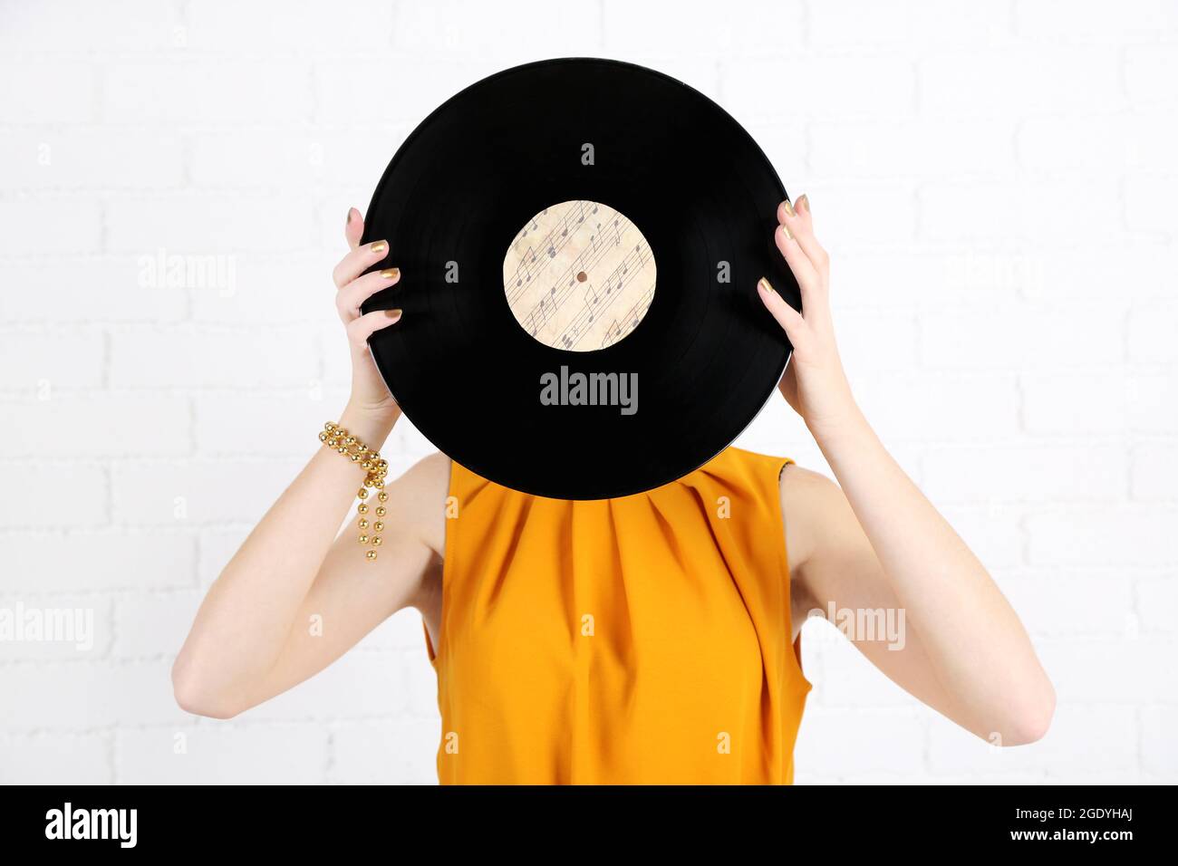 Young woman holding retro record in front of face, on shiny background ...