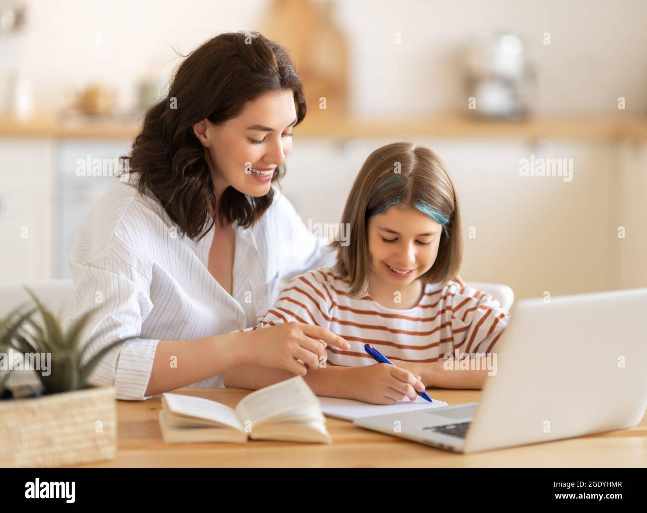 Back to school. Happy child and adult are sitting at desk. Girl doing ...