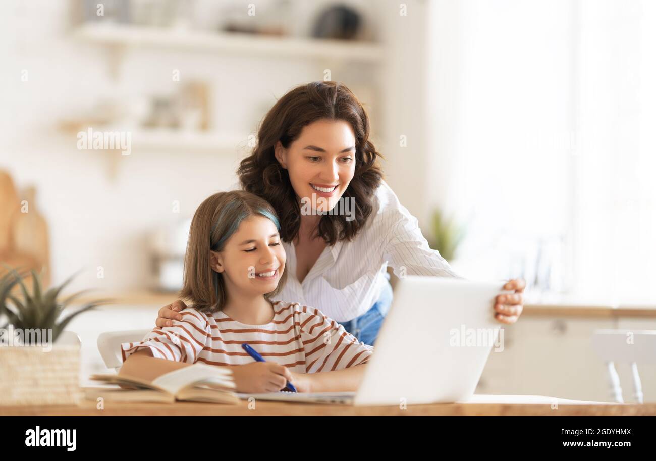 Back to school. Happy child and adult are sitting at desk. Girl doing ...
