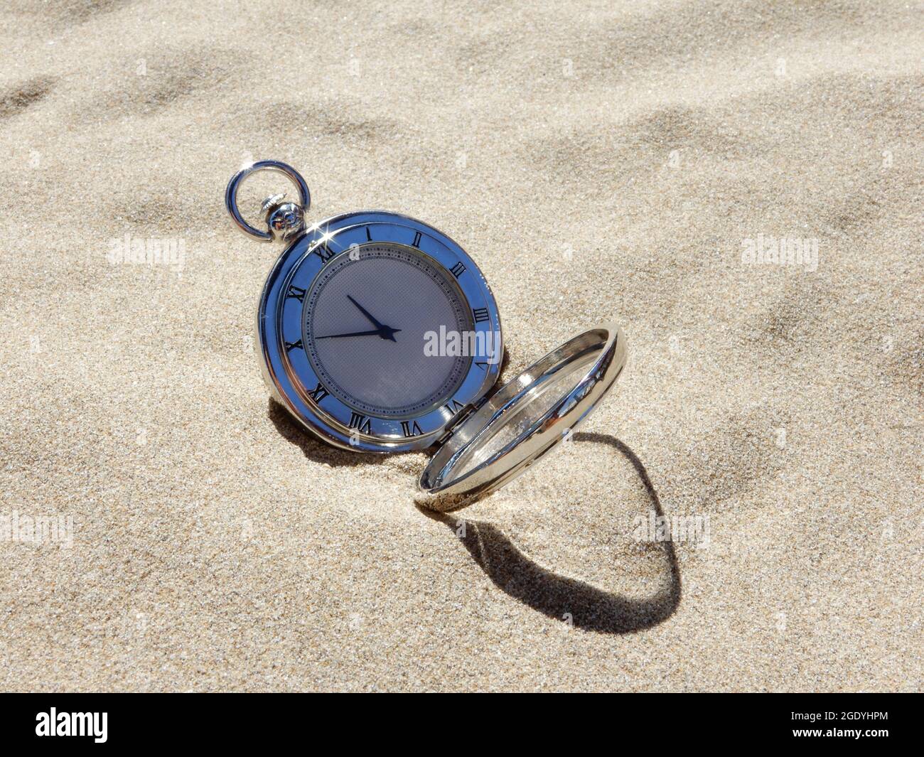 A brightening pocket clock on the sand Stock Photo - Alamy