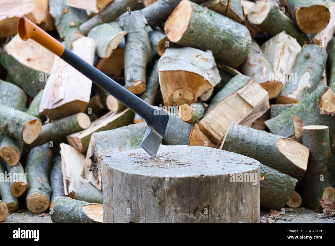 An ax on a tree trunk with firewood on the background Stock Photo - Alamy