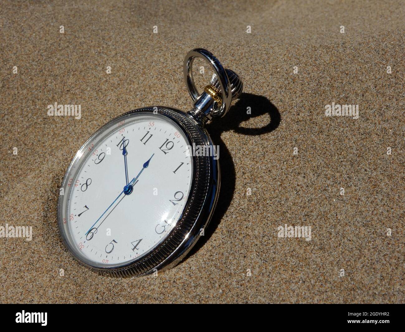 A brightening pocket clock on the sand Stock Photo - Alamy