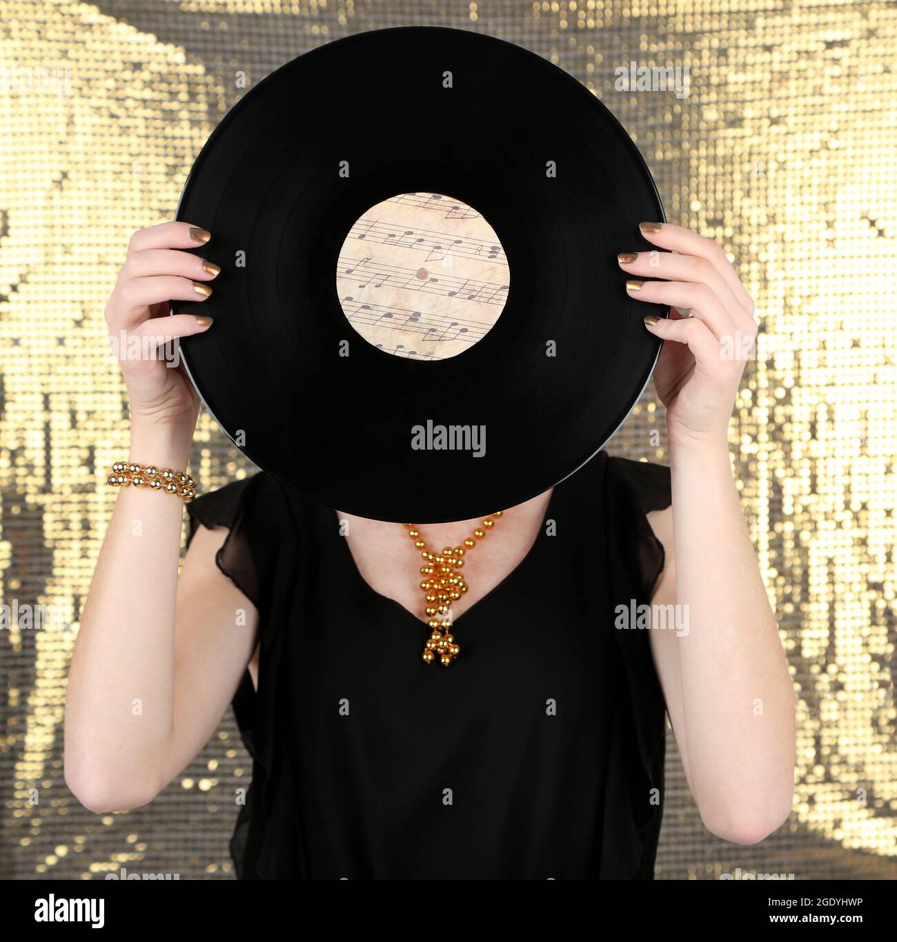 Young woman holding retro record in front of face, on shiny background ...