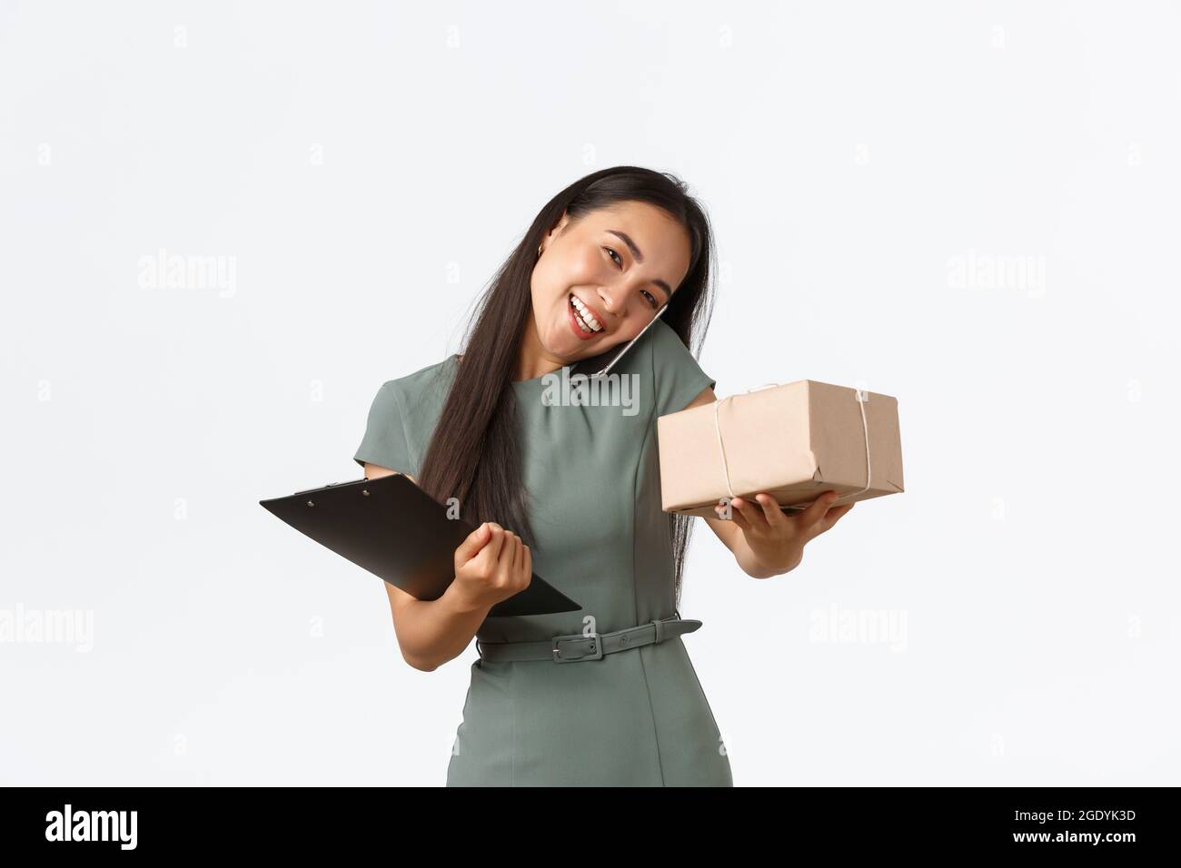 Smiling busy successful female asian store owner, answering phone call ...