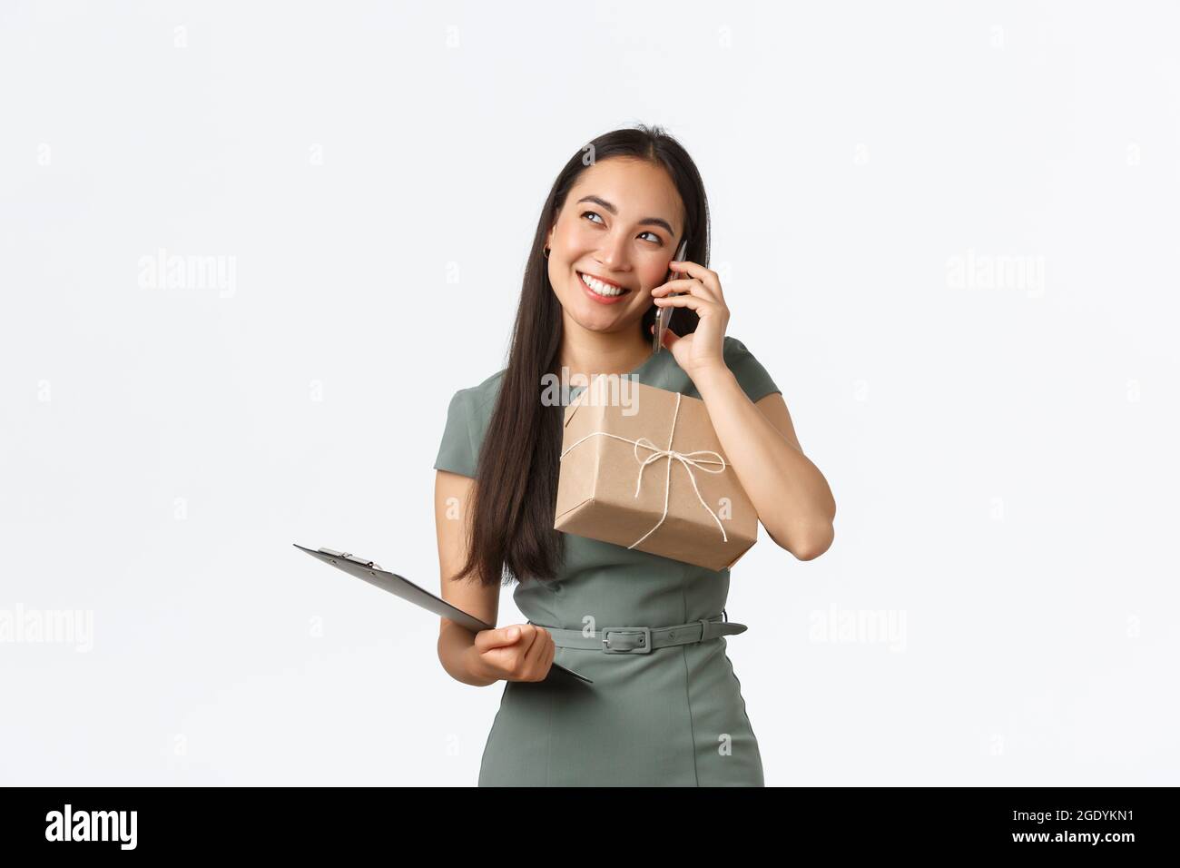 Smiling pretty asian female shop owner in dress, calling customer ...