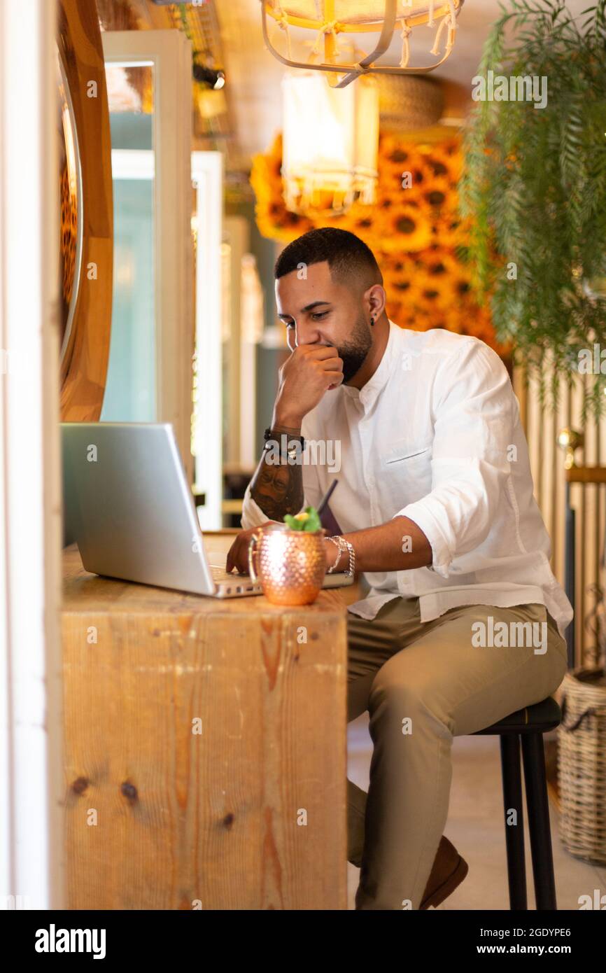 Portrait of young latin american man using a laptop inside a modern ...