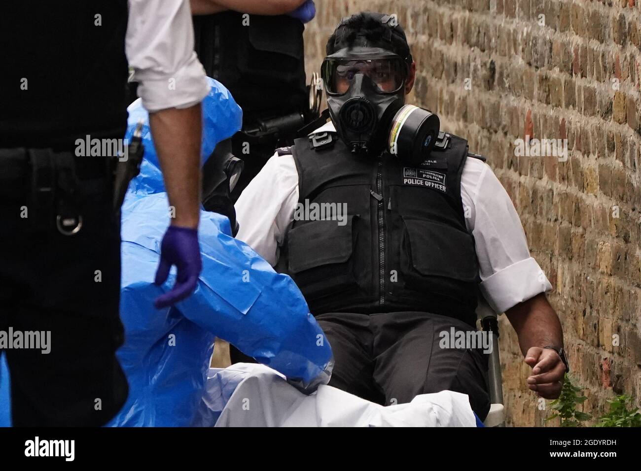 Police officers in bio-hazard suits and breathing apparatus searching a ...