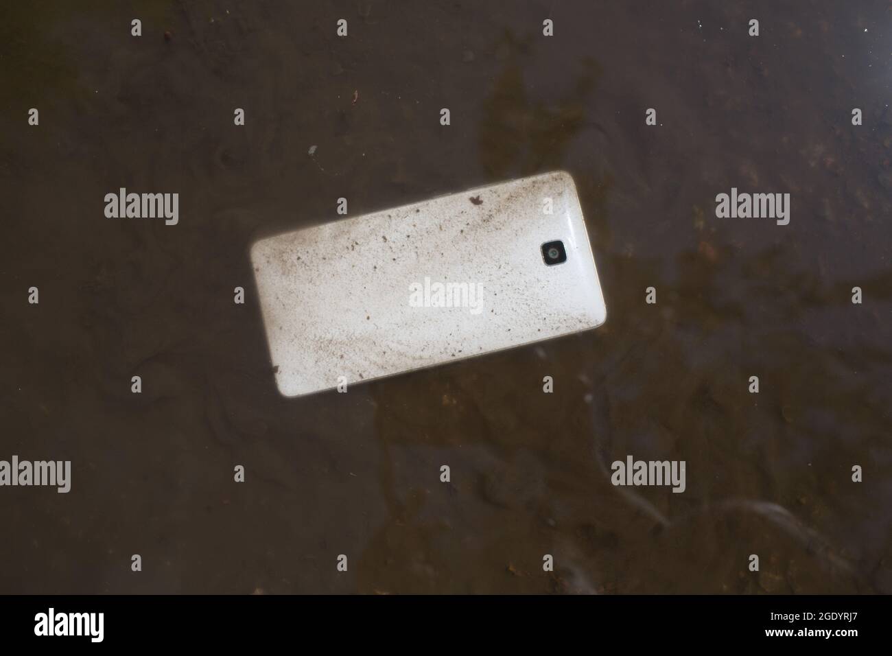 Mobile phone lying on pavement in puddle Stock Photo - Alamy