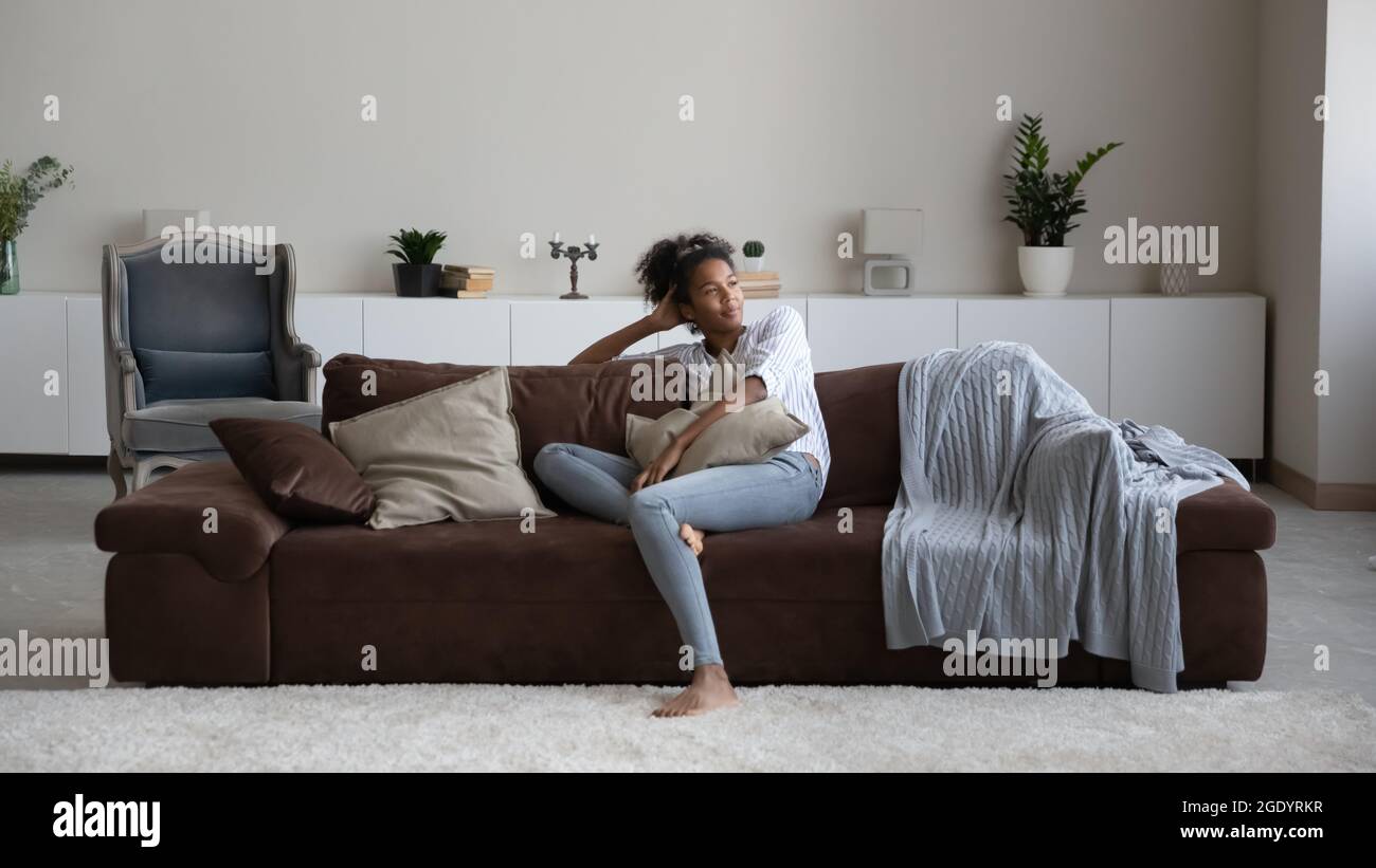 Happy African American woman relax on couch at home Stock Photo - Alamy