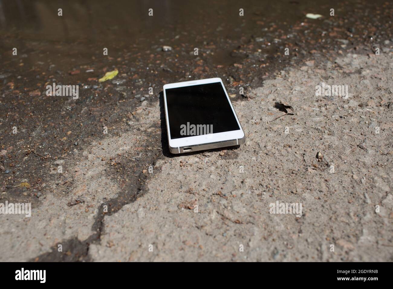 Mobile phone lying on pavement in puddle Stock Photo - Alamy