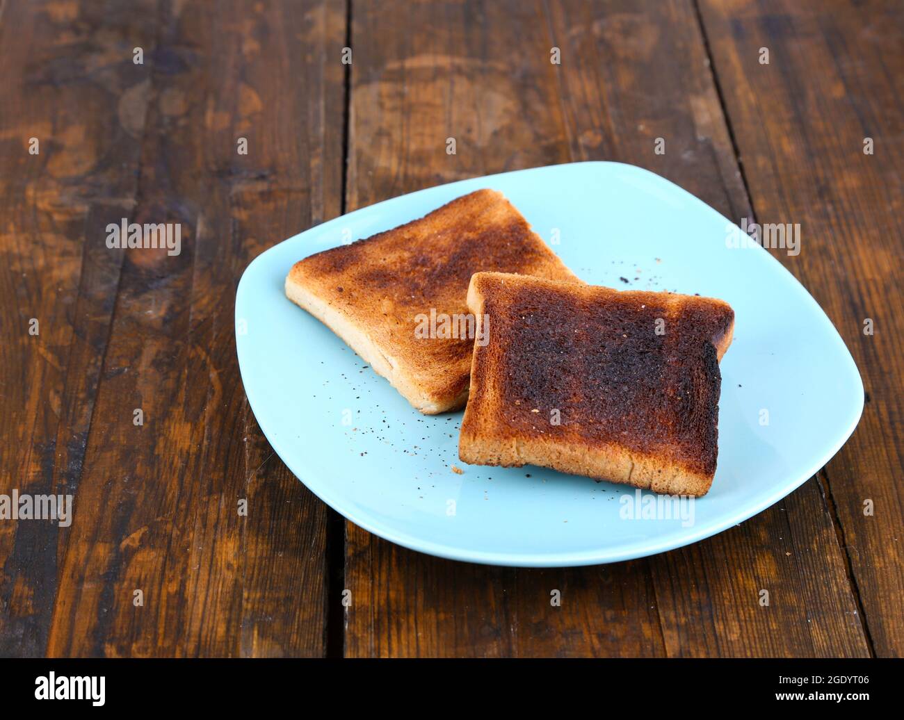 Burnt toast bread on turquoise plate, on wooden table background Stock ...