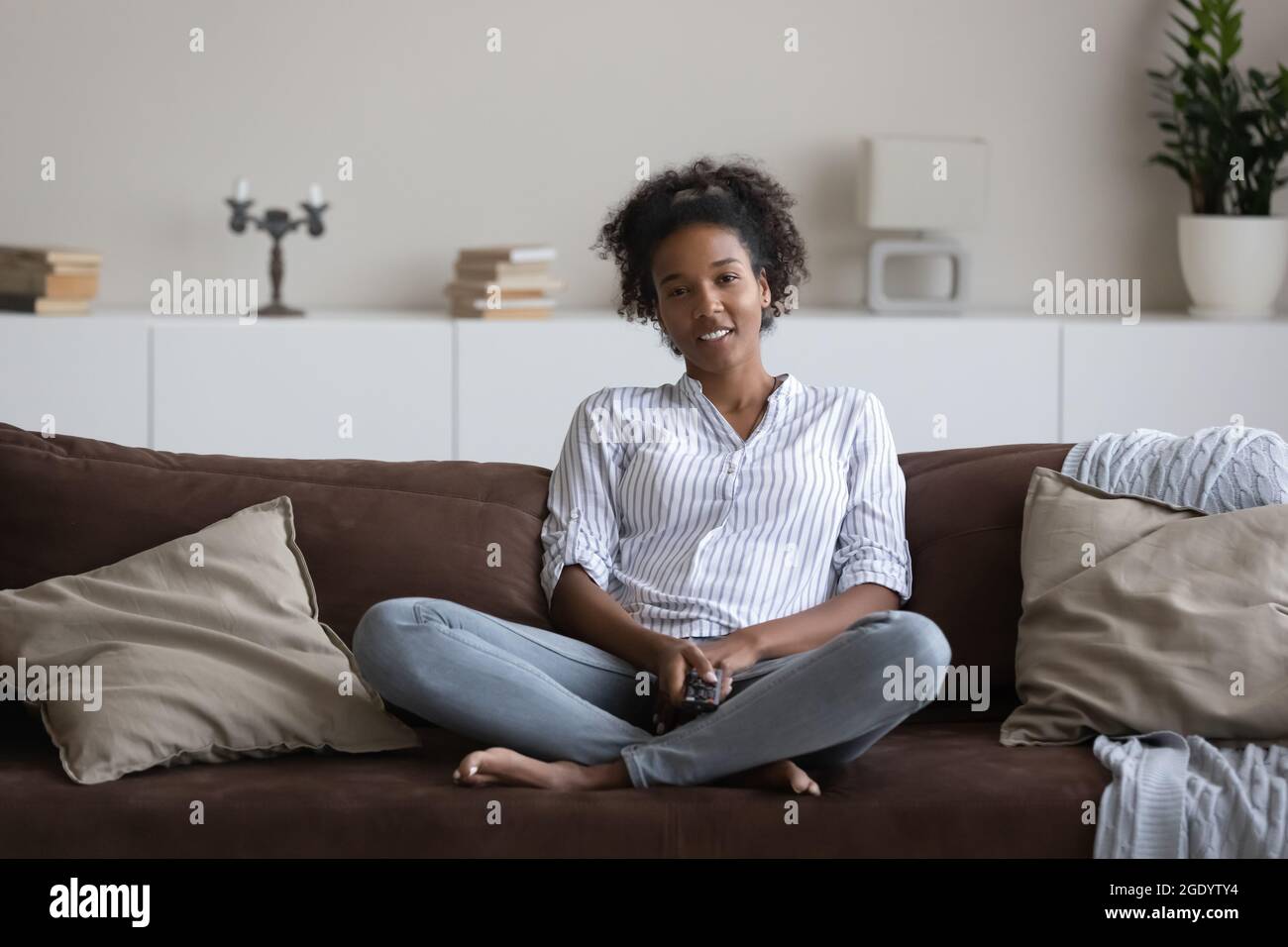 Happy ethnic female renter relax watching TV Stock Photo - Alamy