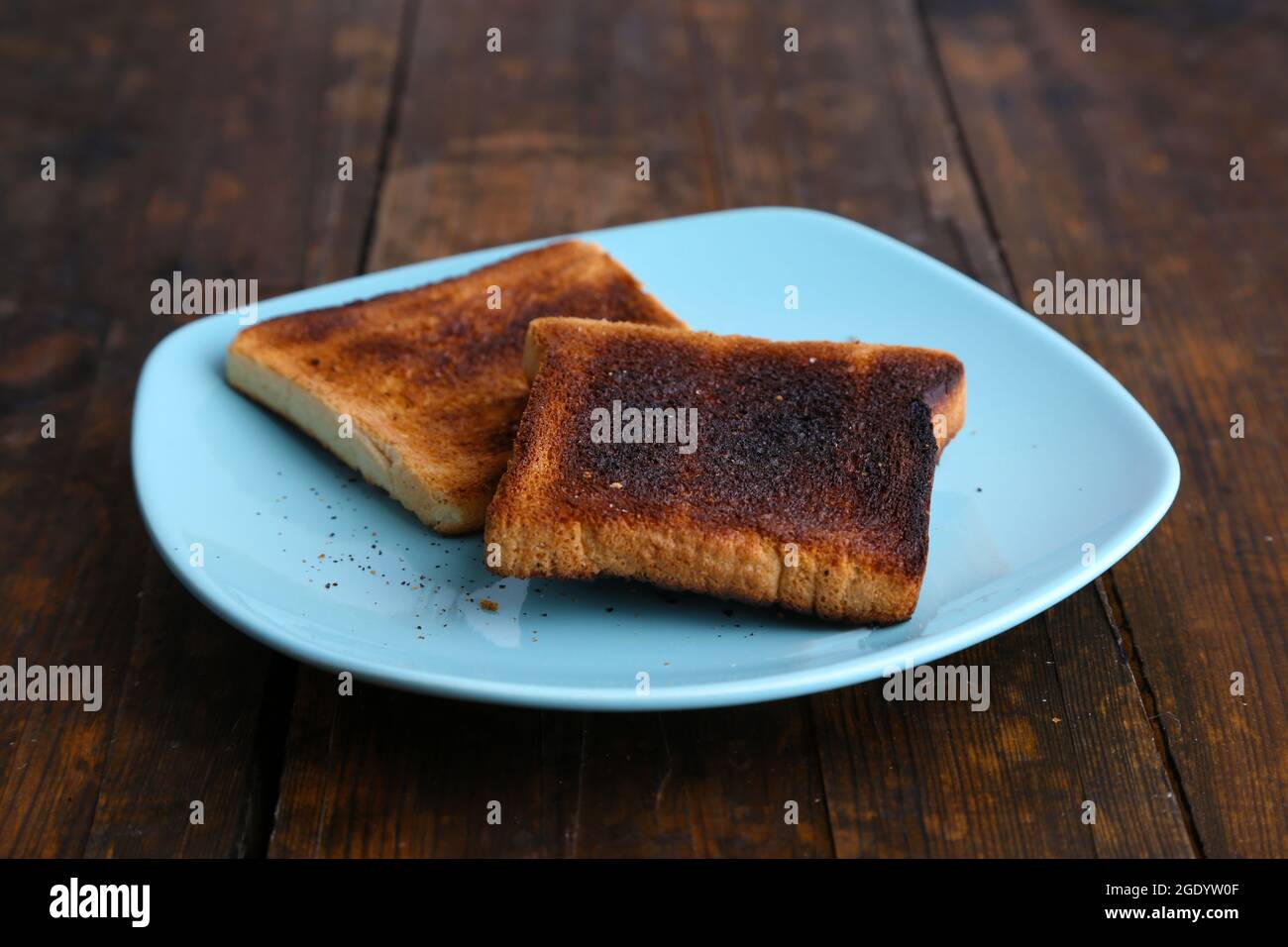 Burnt toast bread on turquoise plate, on wooden table background Stock ...