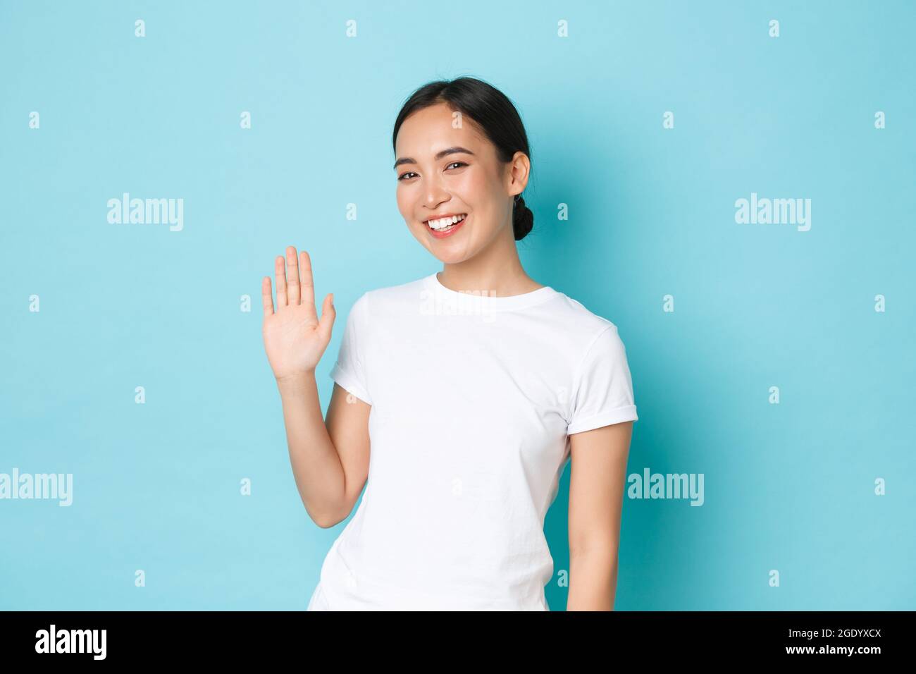 Friendly-looking cheerful asian girl saying hello, greeting new people ...