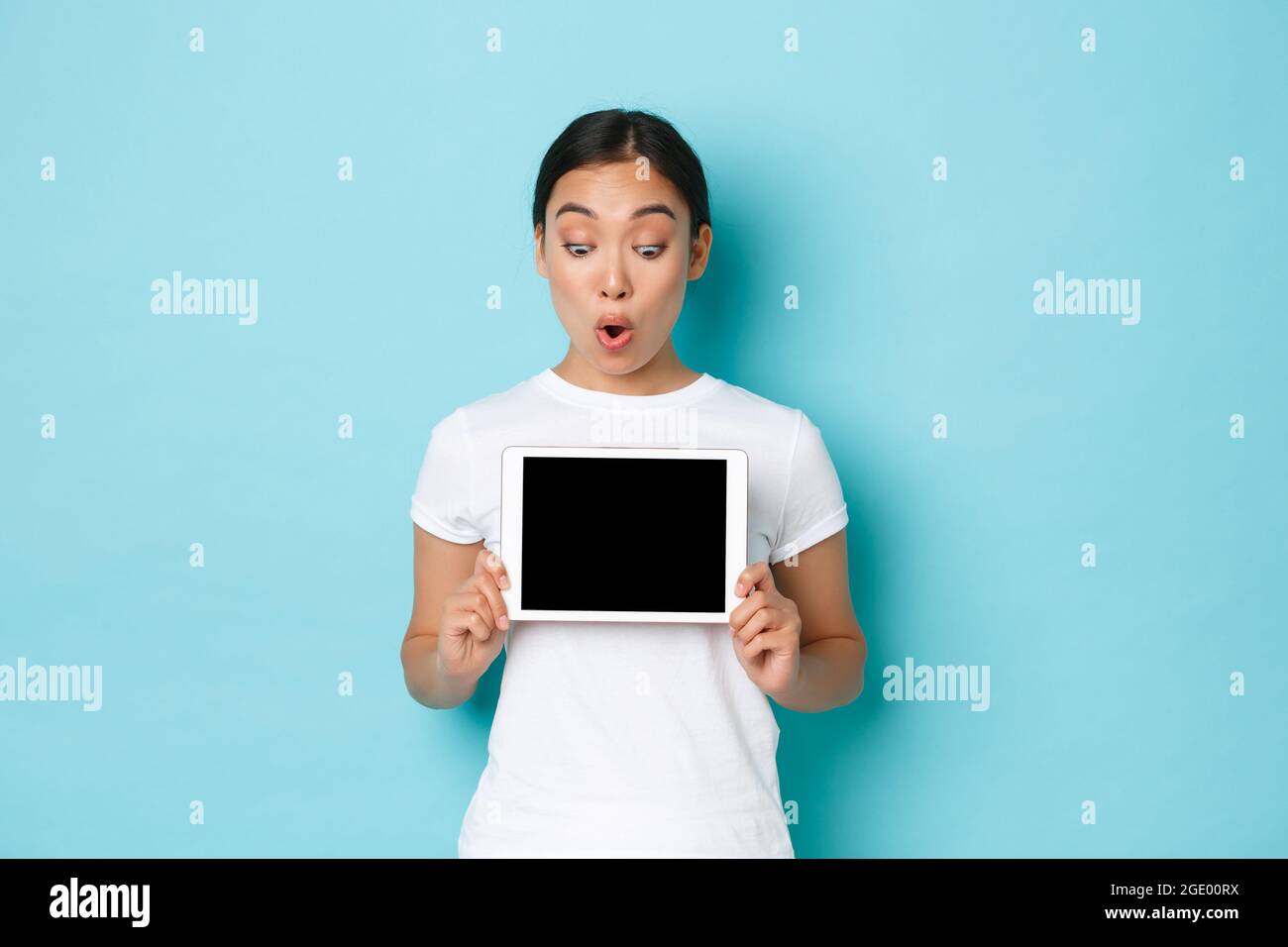 Excited and surprised beautiful asian female in white t-shirt looking ...