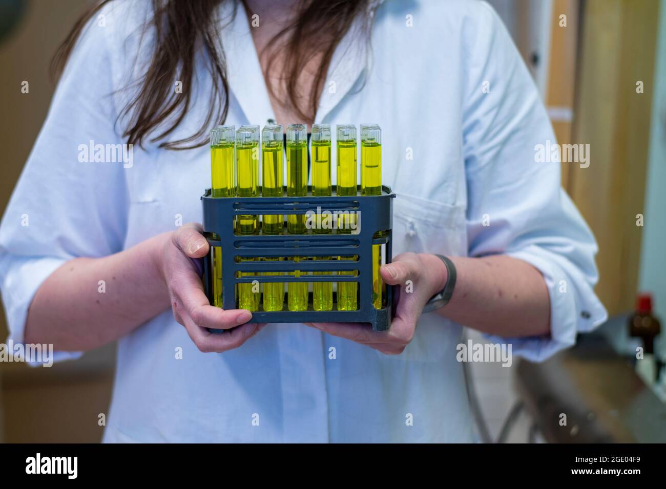 A woman scientist holding fractions of green compound solution ...