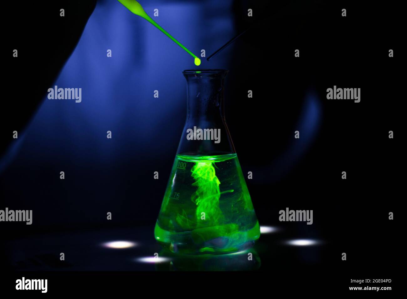 A researcher working with a green fluorescent compound in dark ...