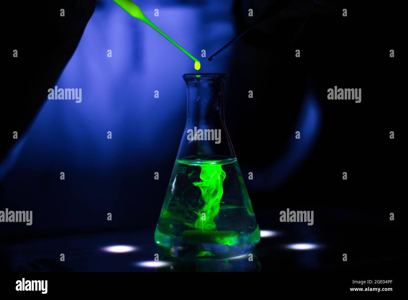 European researcher working with a green fluorescent compound in dark ...