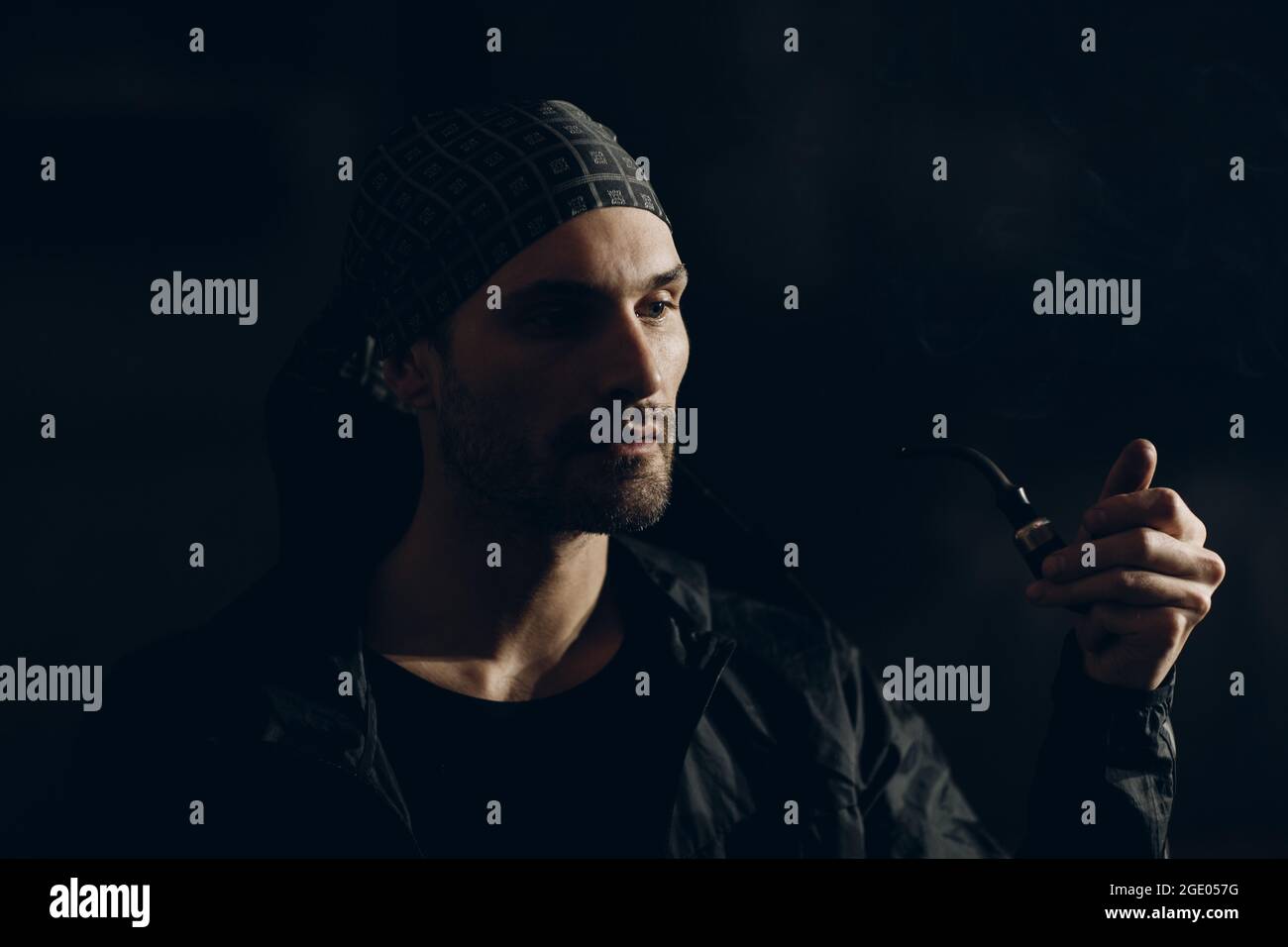 Man smokes smoking pipe against dark background. Back side lit profile ...