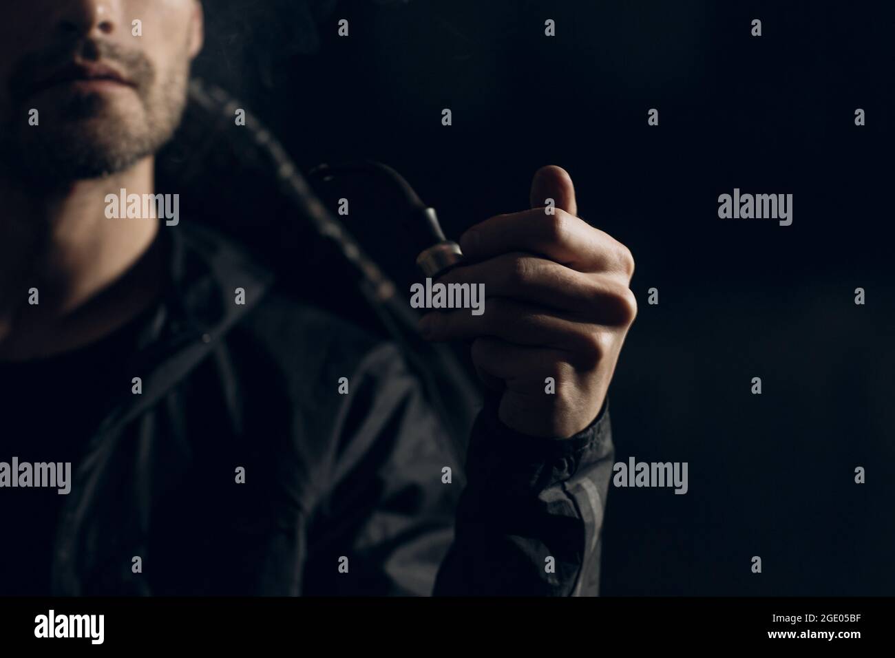 Man smokes smoking pipe against dark background. Back side lit profile ...
