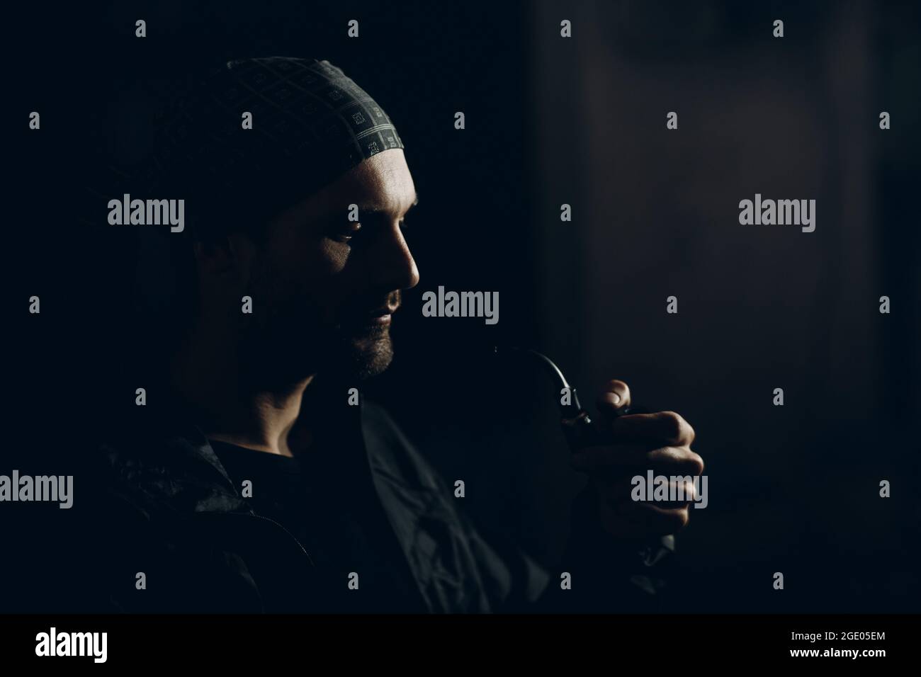 Man smokes smoking pipe against dark background. Back side lit profile ...