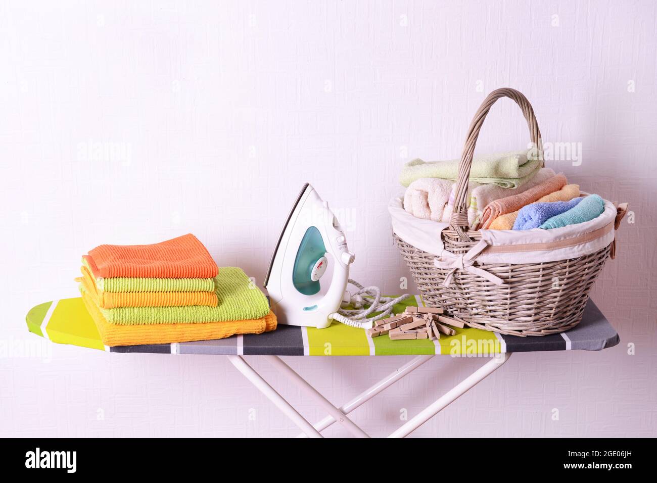 Ironing board with laundry on light background Stock Photo - Alamy