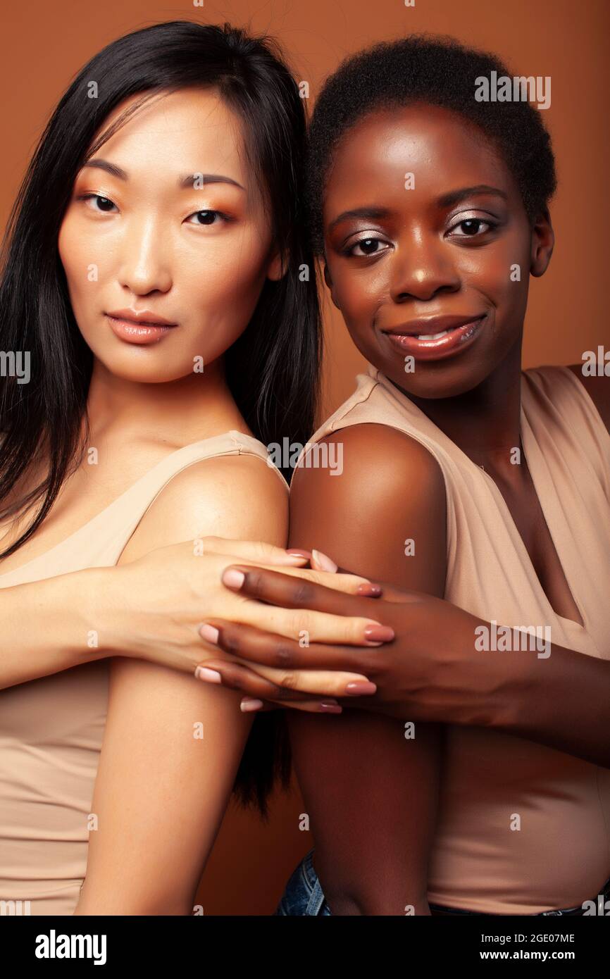young pretty asian, afro woman posing cheerful together on brown ...