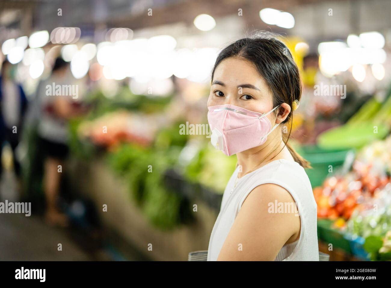 A beautiful Southeast Asian female in the market with a mask on her ...