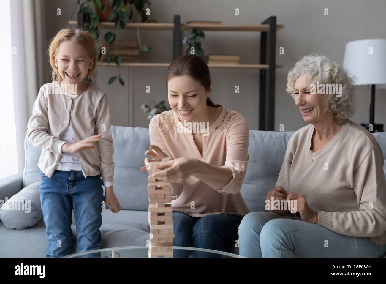 Happy three generations of women play wooden game Stock Photo - Alamy