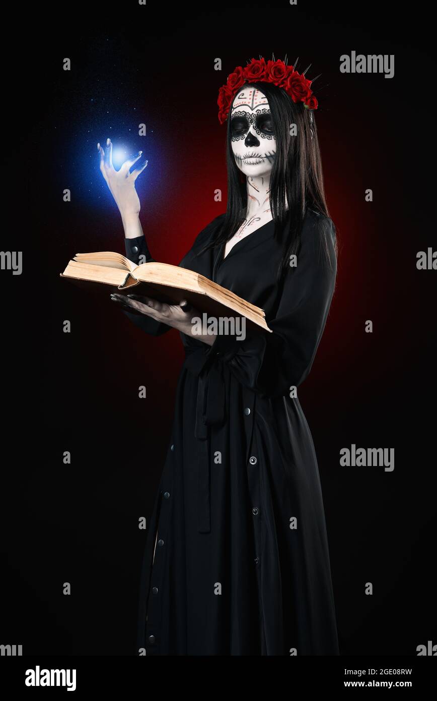 Young woman with calavera (sugar skull) makeup holds book (grimoire ...
