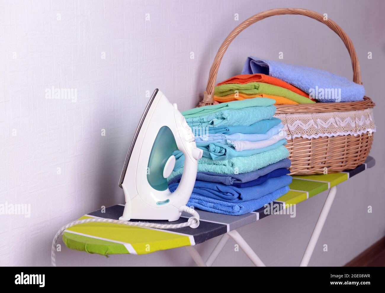 Ironing board with laundry on light background Stock Photo - Alamy