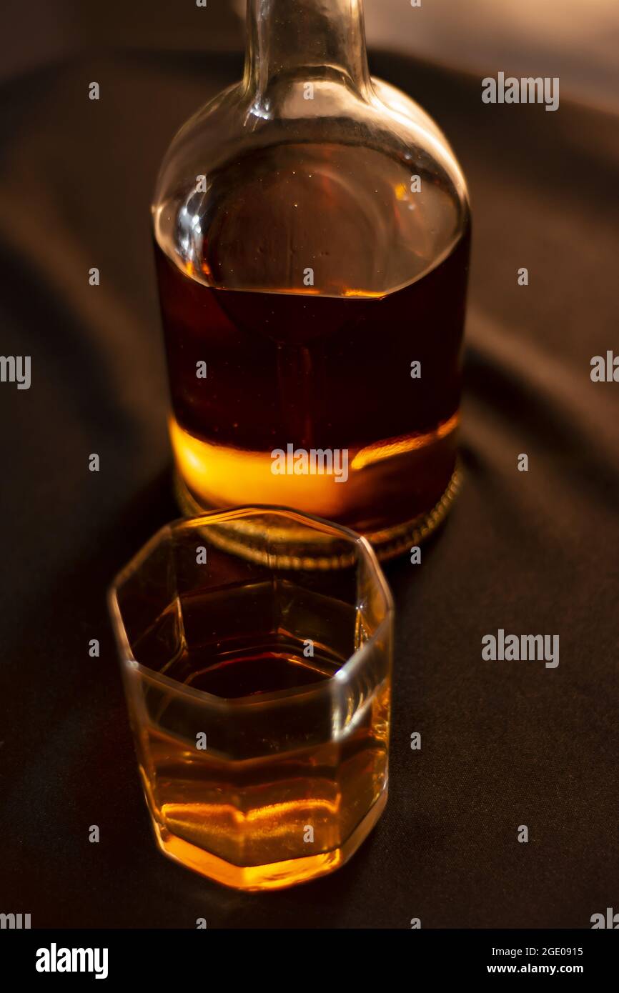 A high angle shot of bottle and a glass of amber-colored whisky on ...