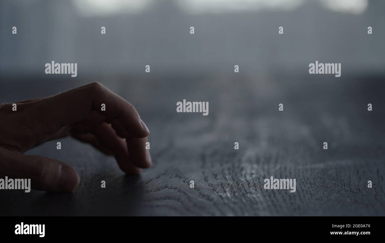 Man tapping fingers on black oak table with back light, wide photo ...