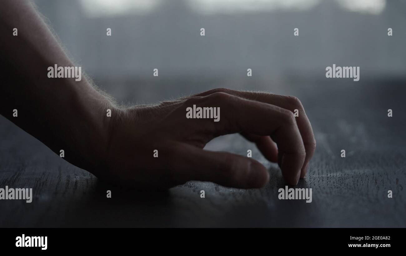 Man tapping fingers on black oak table with back light, wide photo ...