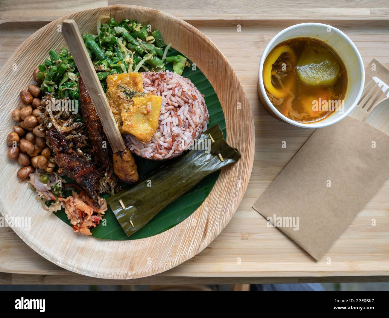 Top down view of a plate of Balinese food with fish, sate, soup, rice ...