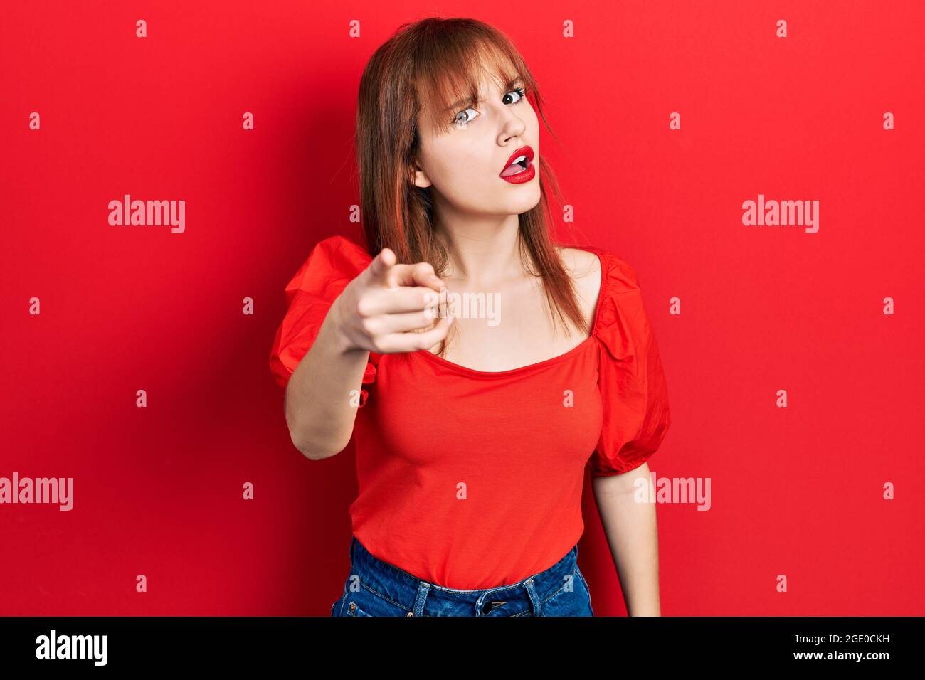 Redhead young woman wearing casual red t shirt pointing displeased and ...