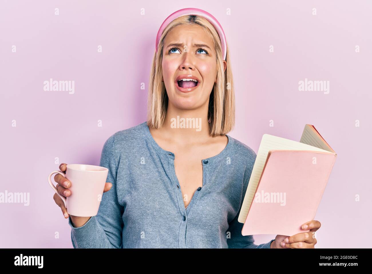 Beautiful blonde woman reading a book and drinking a cup of coffee ...