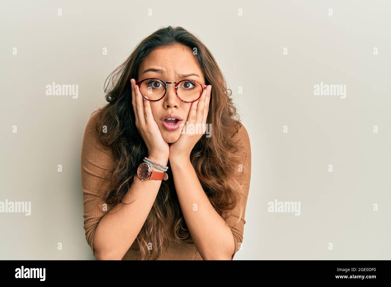 Young hispanic girl wearing casual clothes and glasses afraid and ...