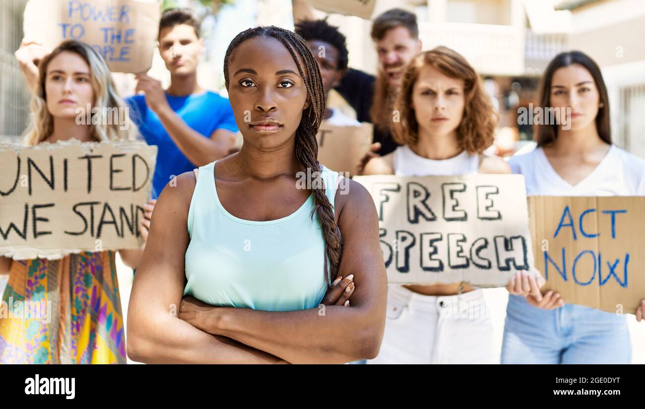 Young activist woman with arms crossed gesture standing with a group of ...