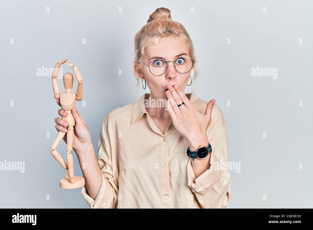 Beautiful caucasian woman with blond hair holding small wooden manikin ...