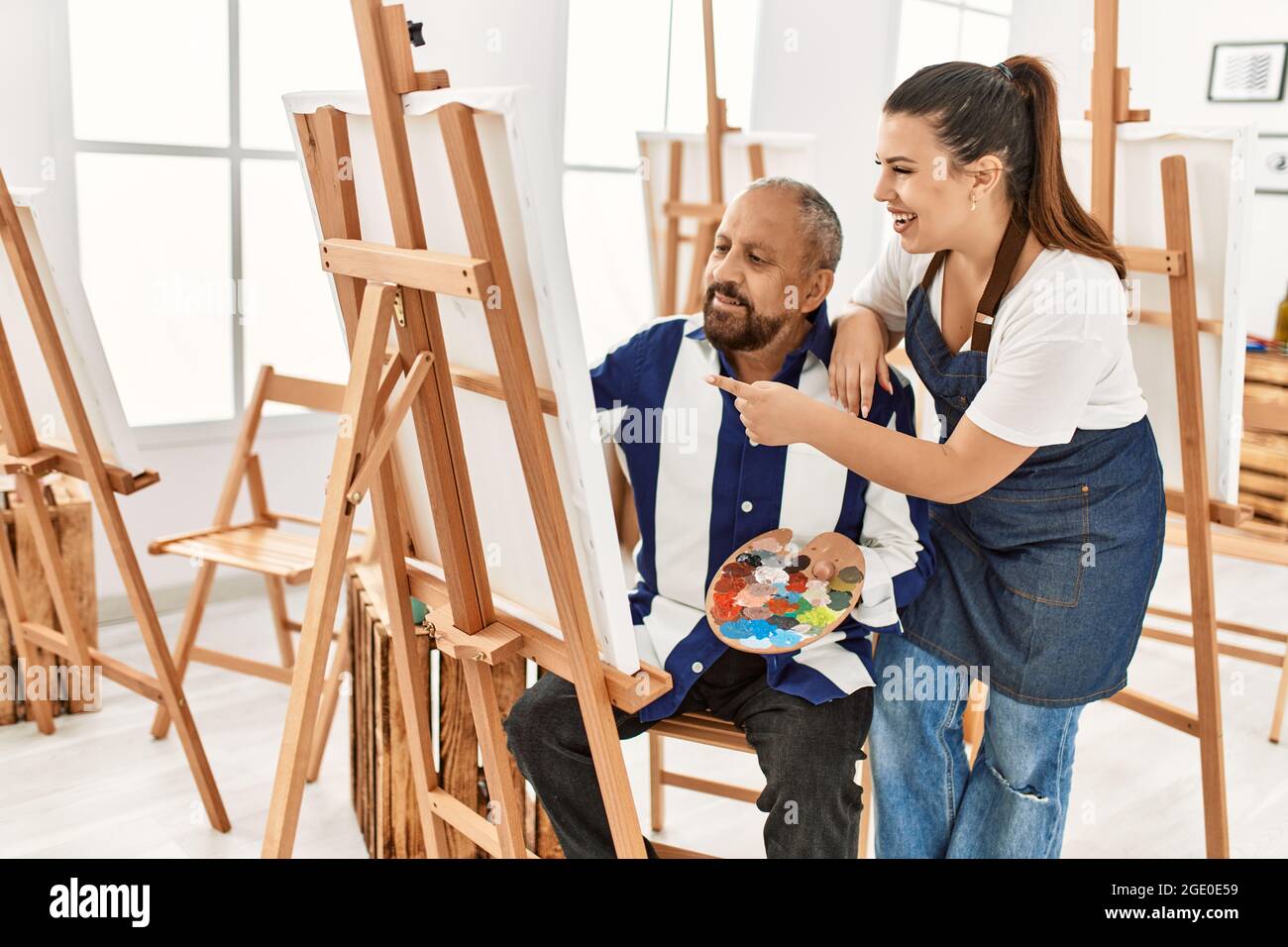 Young painting teacher woman teaching art to senior man painting on ...