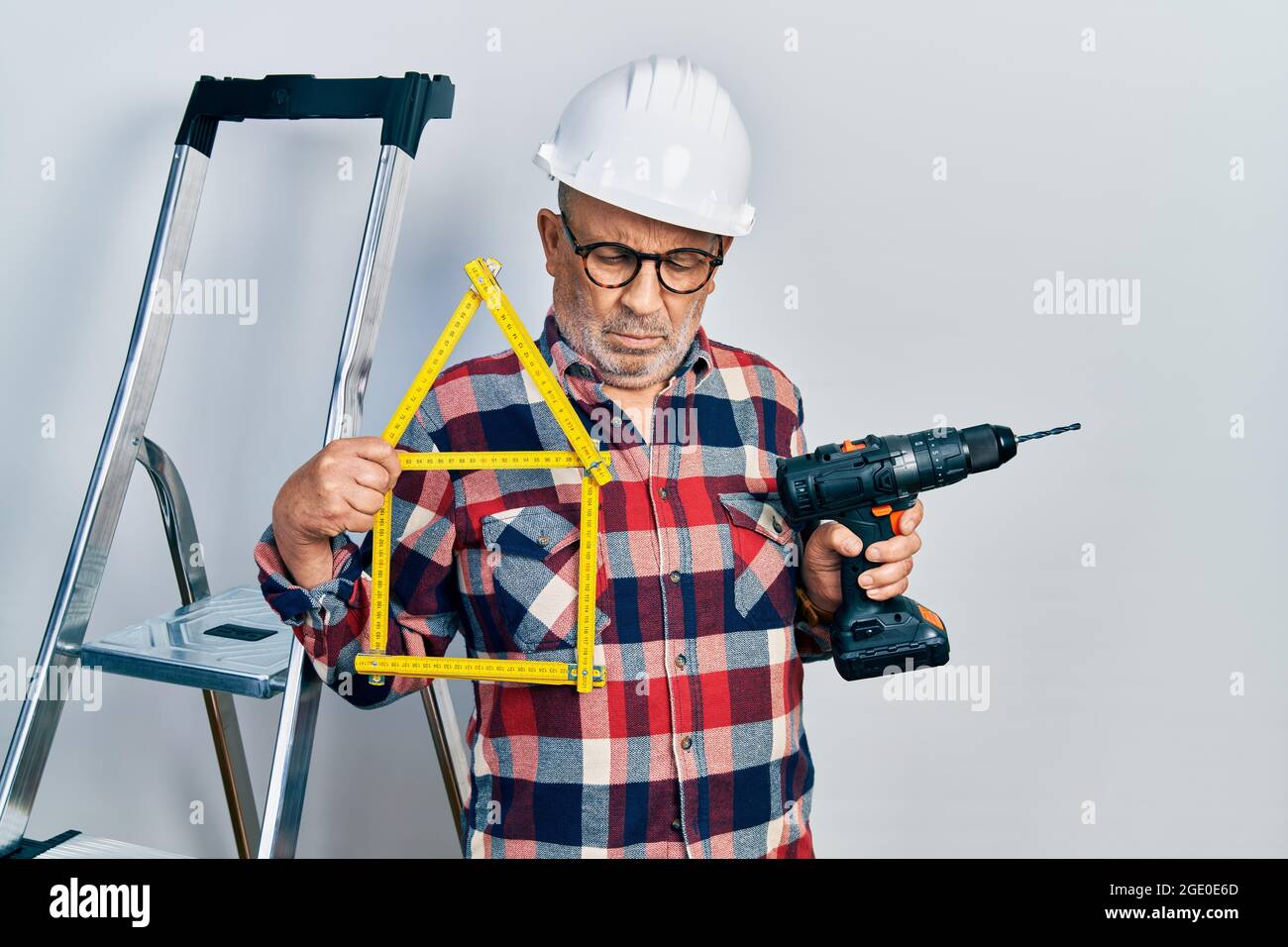 Handsome mature handyman holding screwdriver wearing hardhat by ...