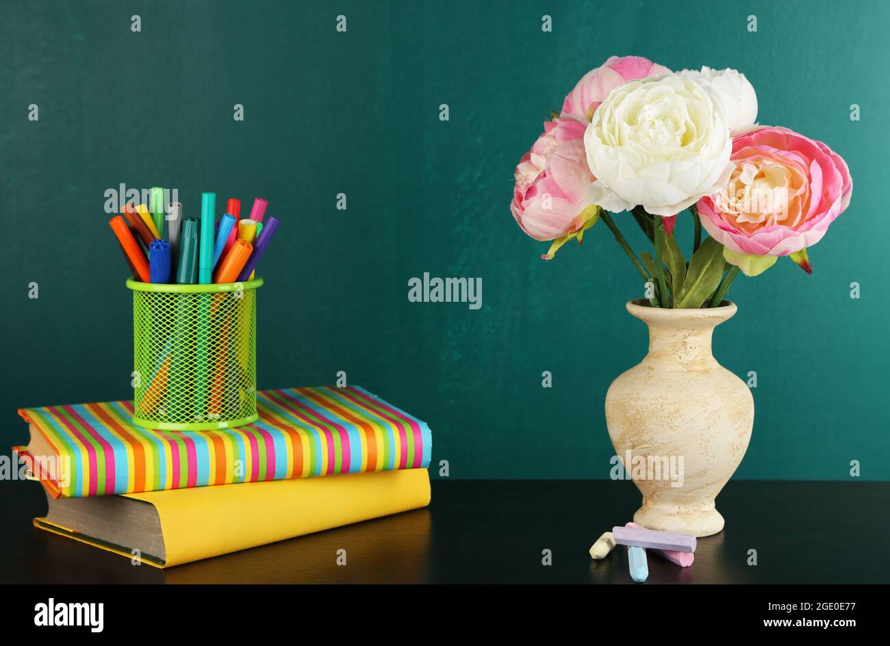 Composition on desk with books and flowers on green blackboard ...