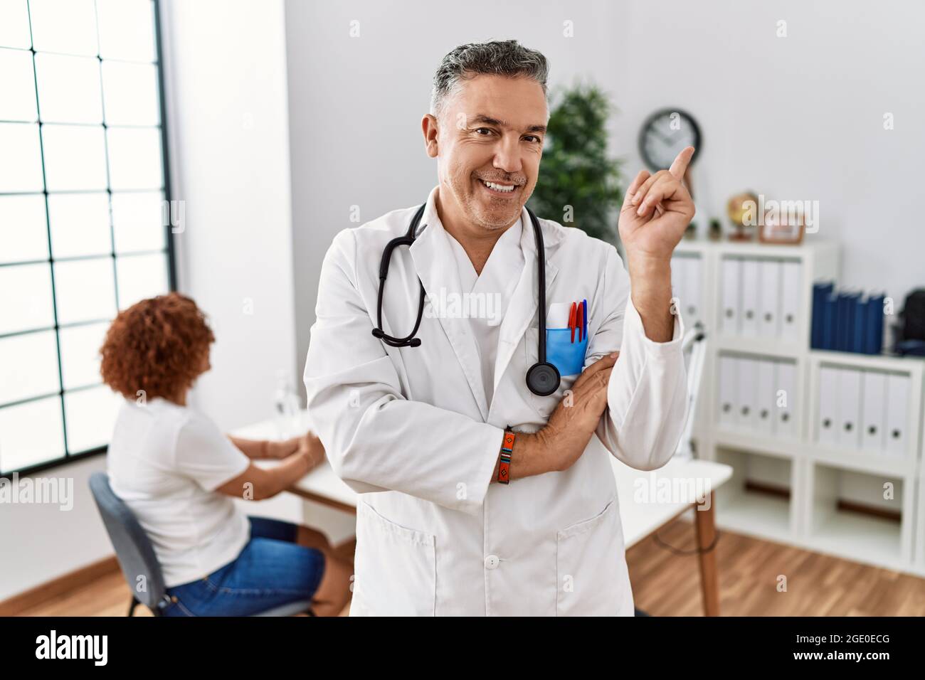 Middle age doctor man at the clinic with a patient with a big smile on ...