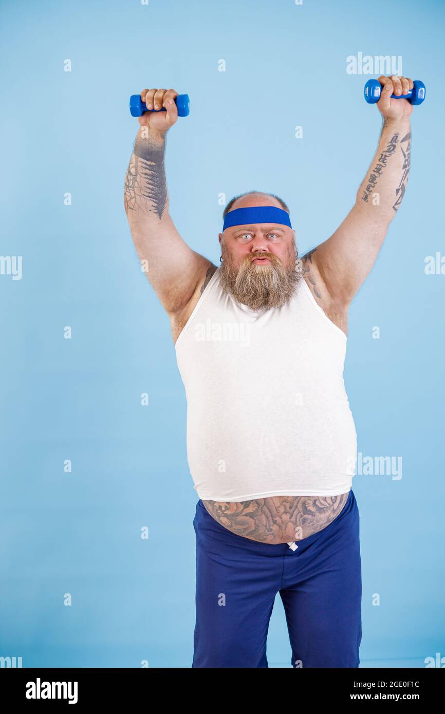 Fat man does sports exercises with dumbbells trying to loss weight on ...