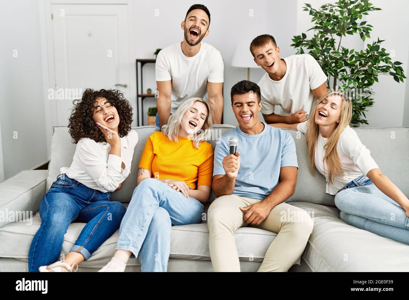Group of young friends having party singing song using microphone at ...