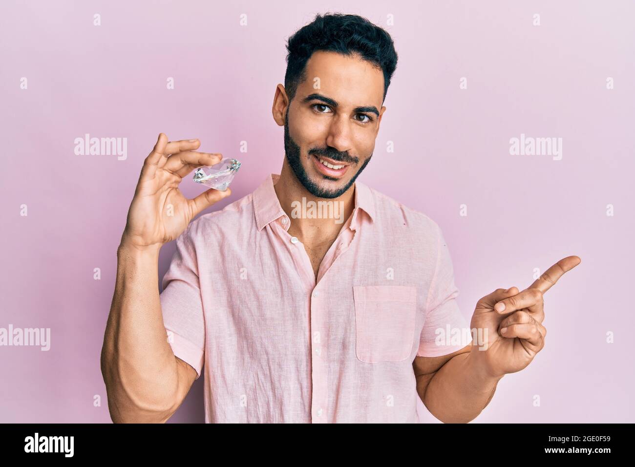 Young hispanic man holding brilliant diamond stone smiling happy ...