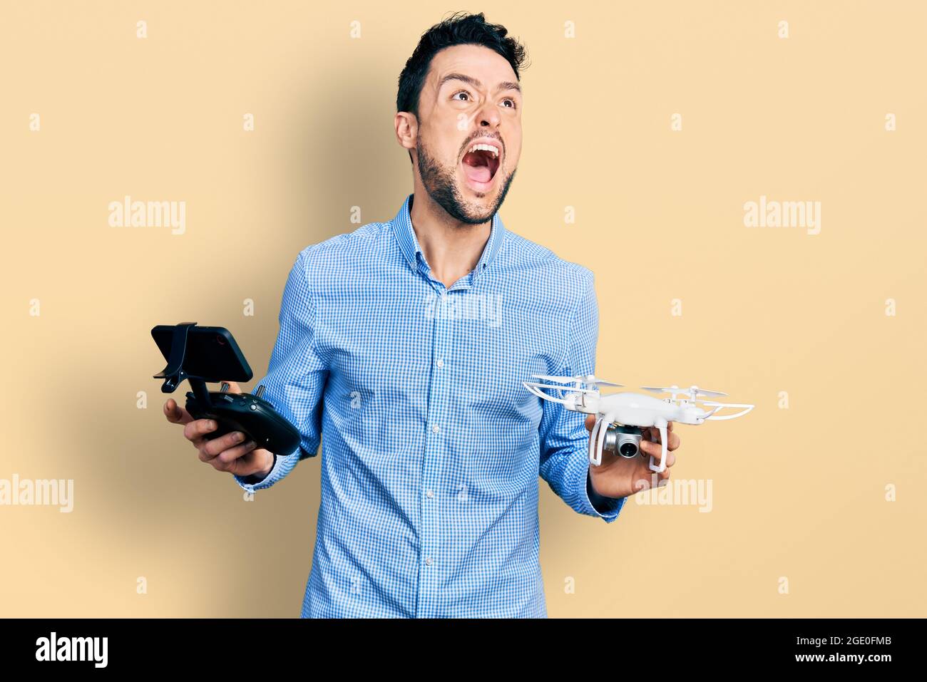 Hispanic man with beard using drone with remote control angry and mad ...