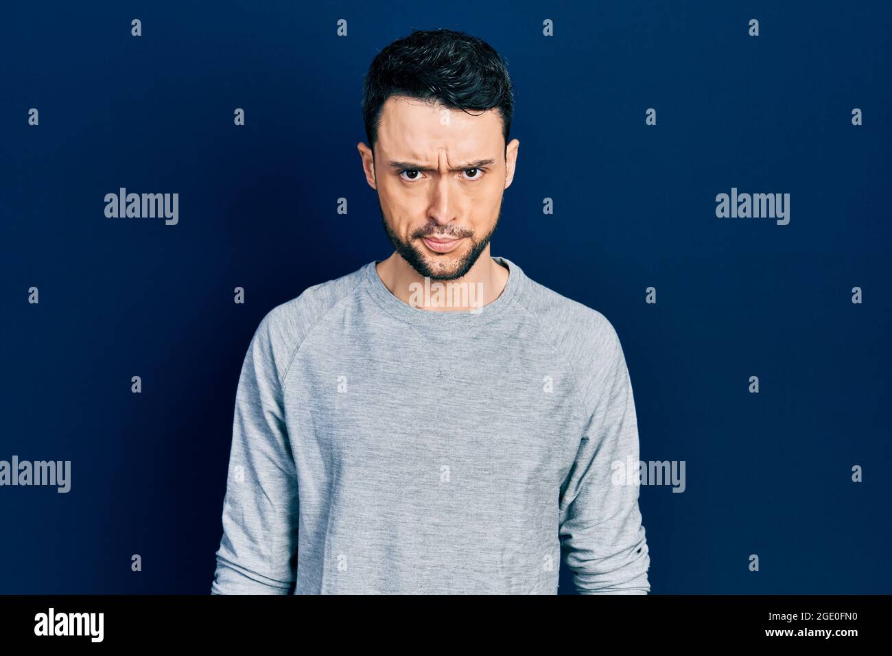 Young hispanic man wearing casual clothes skeptic and nervous, frowning ...